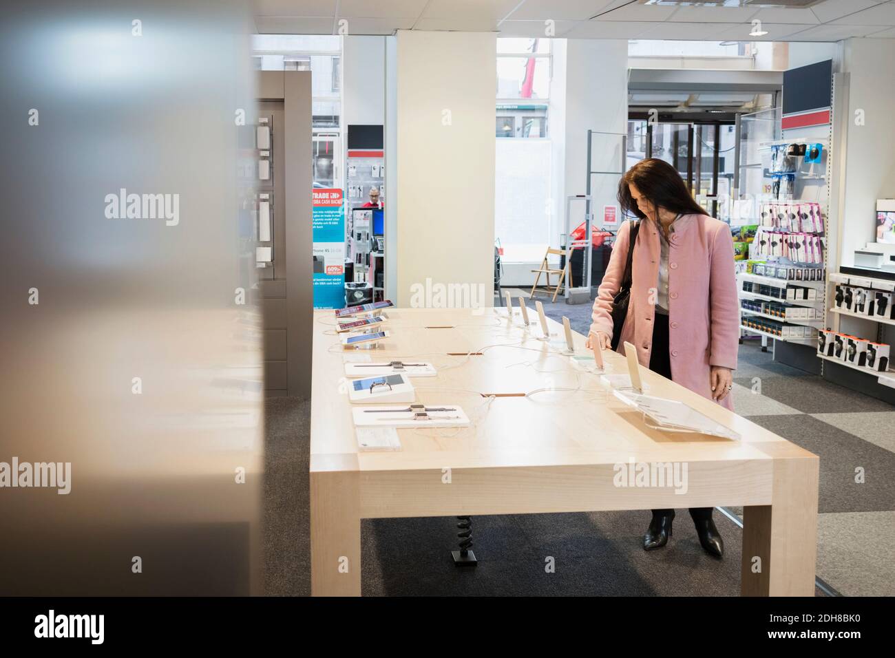 Female customer viewing technologies at table in showroom Stock Photo ...