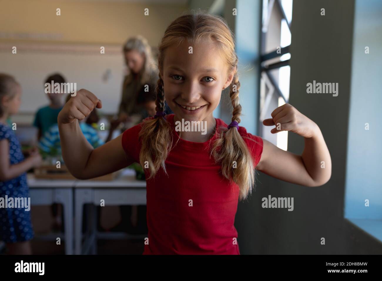 Schoolgirl standing flexing her bicep muscles in an elementary school ...