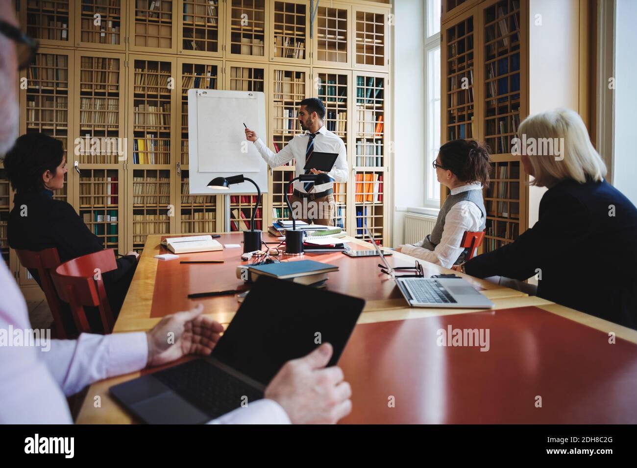 Male professional giving presentation to coworkers in board room Stock ...