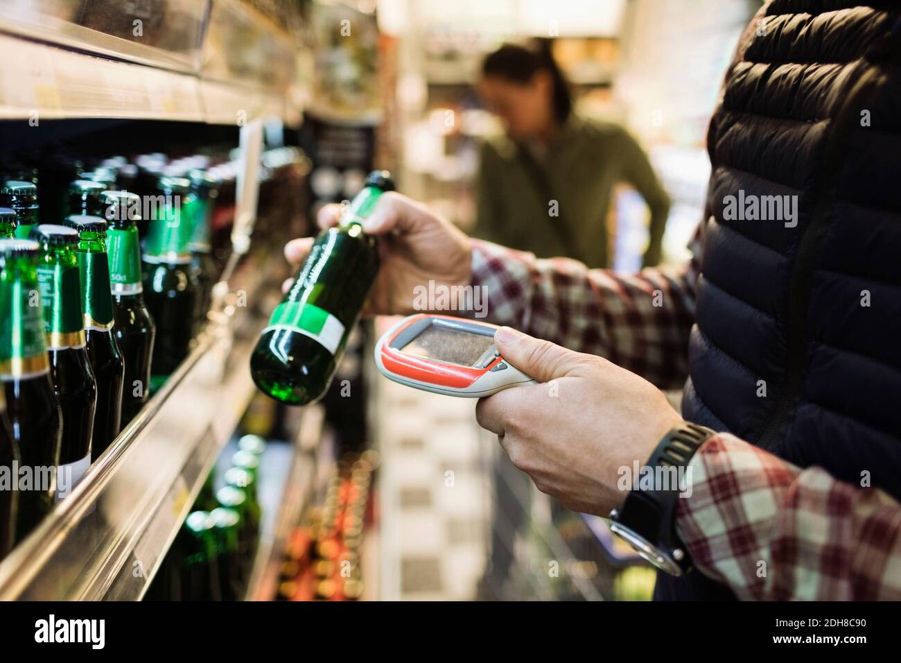 Midsection of male customer scanning beer bottle in supermarket Stock ...