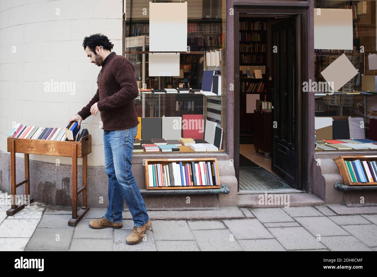 Customer searching book while standing on sidewalk outside library ...