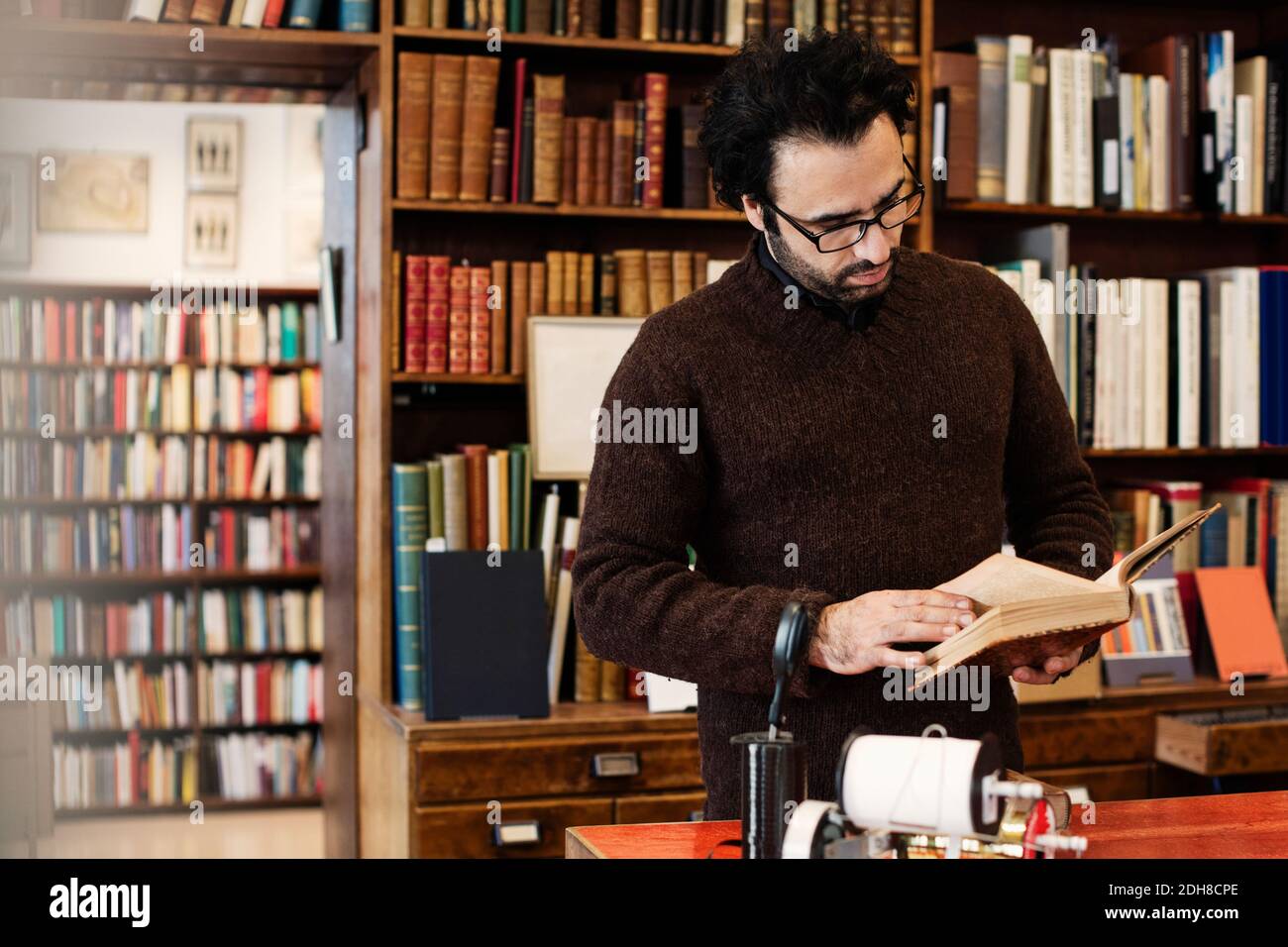 Owner reading book while standing in store Stock Photo - Alamy