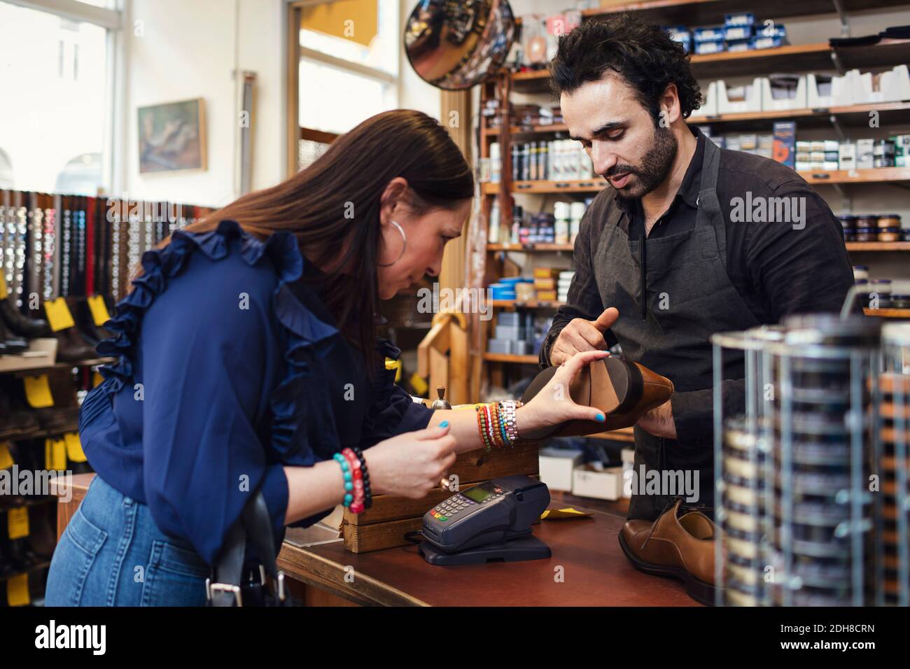 Shoemaker showing shoe to female customer in store Stock Photo - Alamy
