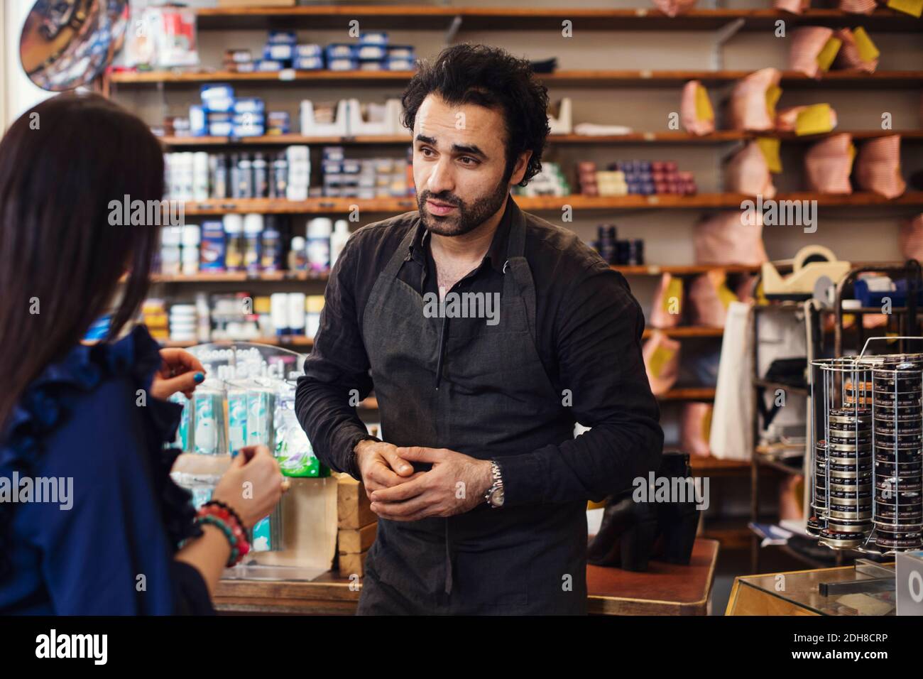 Rear view of female customer talking with man at shoe repair store ...