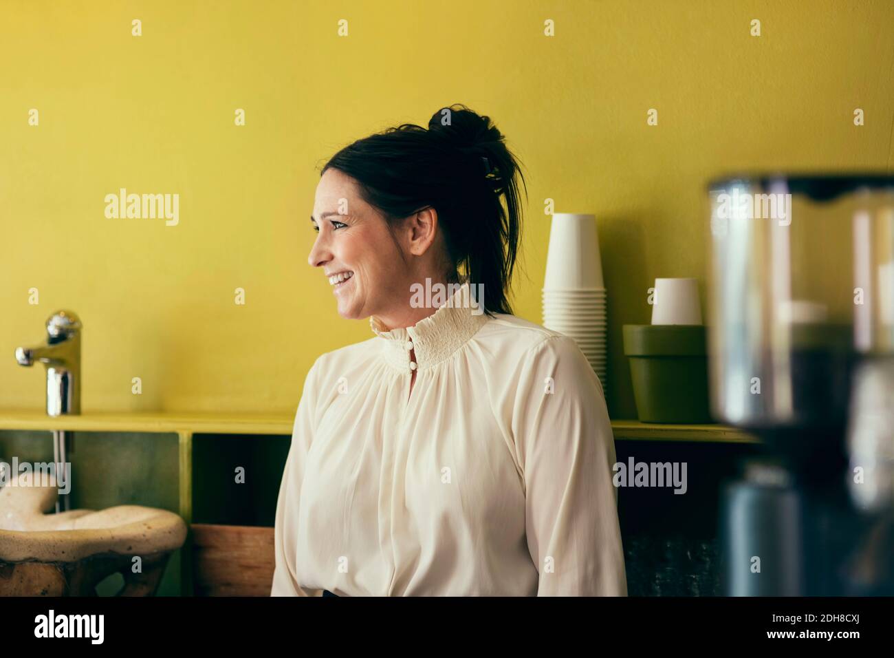 Happy waitress looking away in coffee shop Stock Photo - Alamy