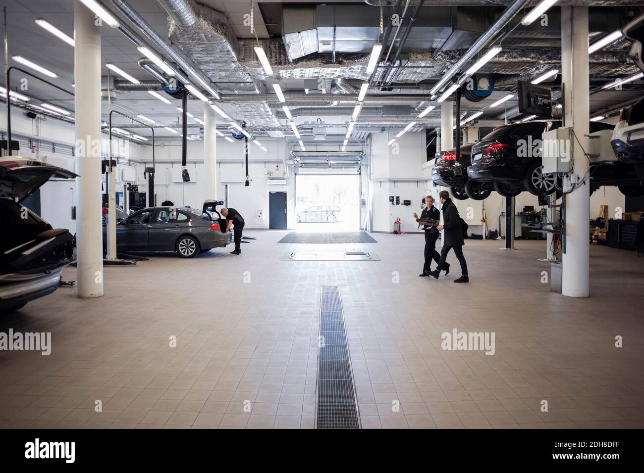 Female mechanic walking with client in auto repair shop Stock Photo - Alamy