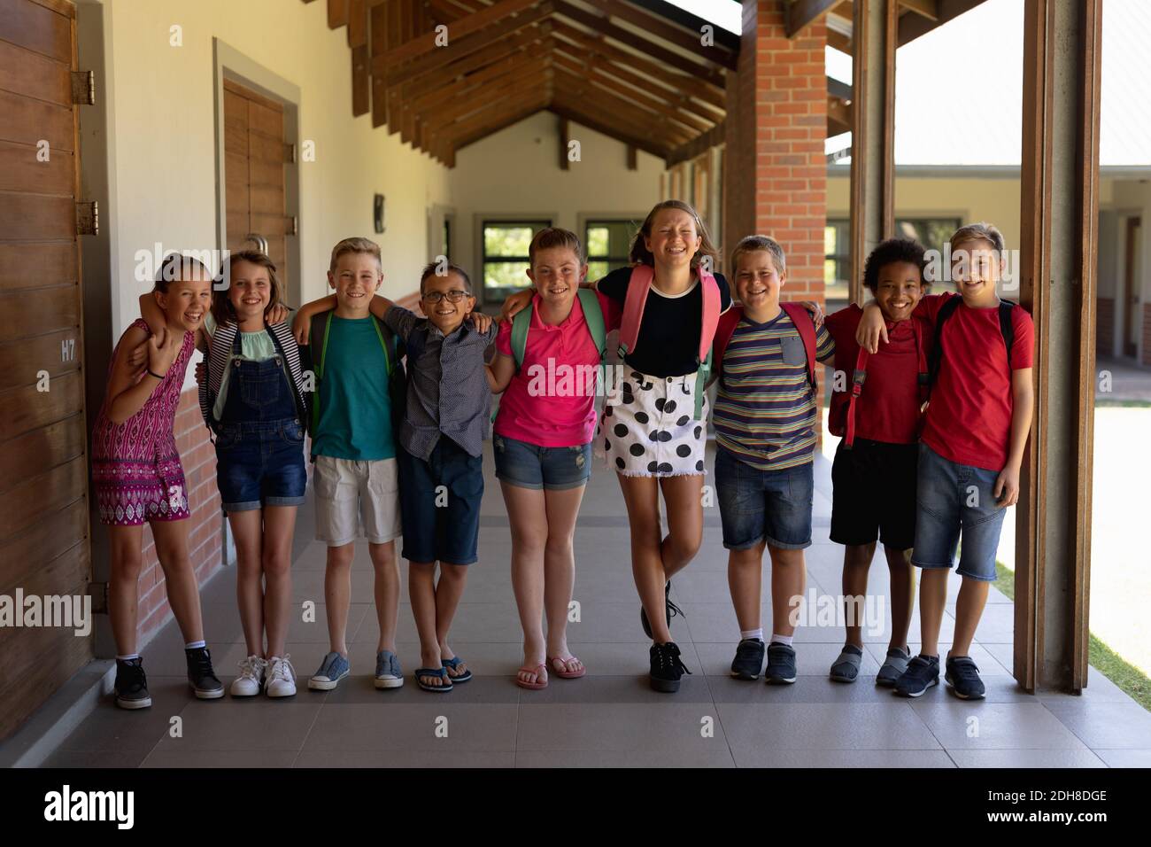 Group of schoolchildren walking in a line with arms around each other ...