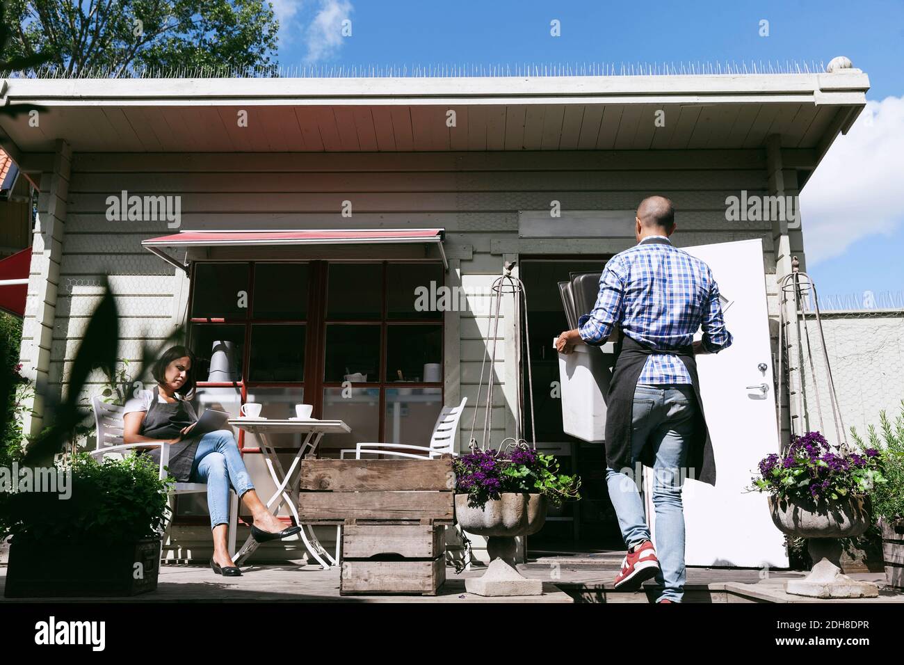 Man carrying serving trays while walking by woman working at table ...