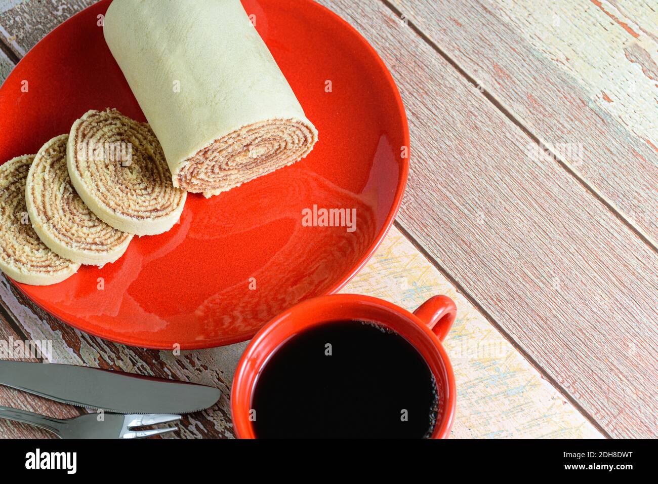 Bolo de rolo (roll cake) with silverware and a cup of coffee (top view ...