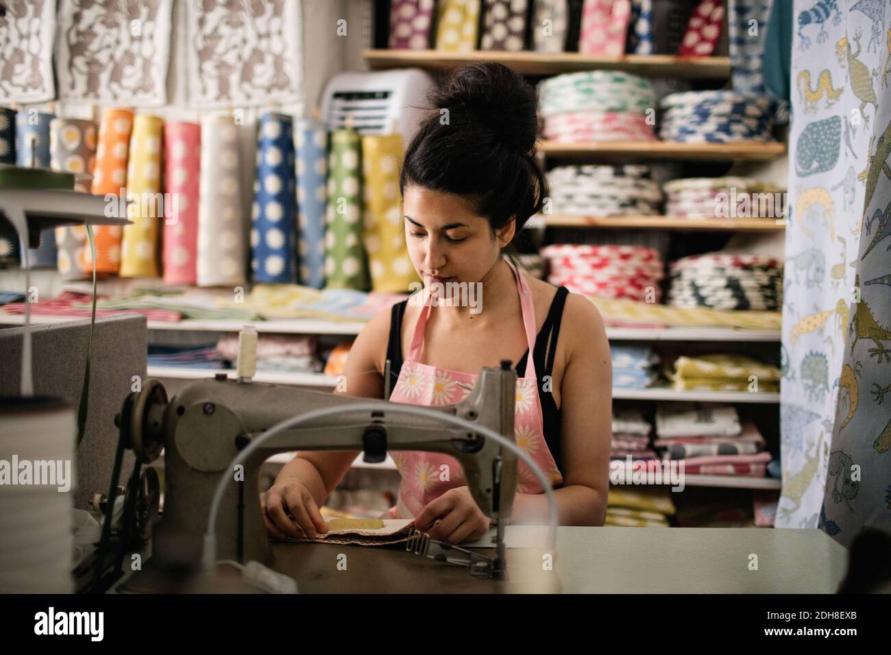 Woman sewing textile while working in fabric shop Stock Photo - Alamy