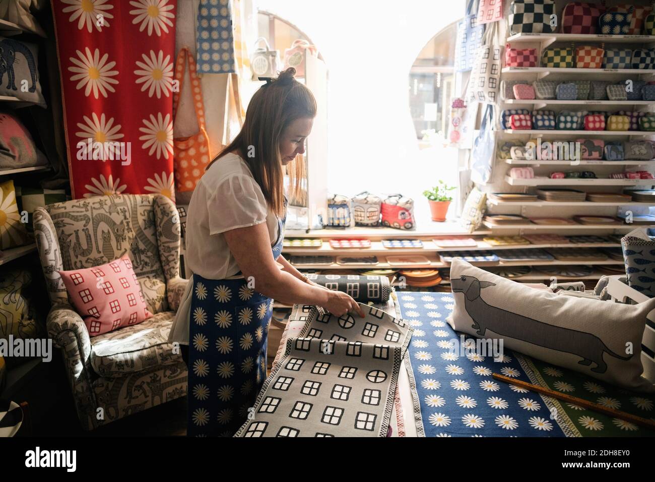 Serious woman cutting fabric swatch while working in shop Stock Photo ...