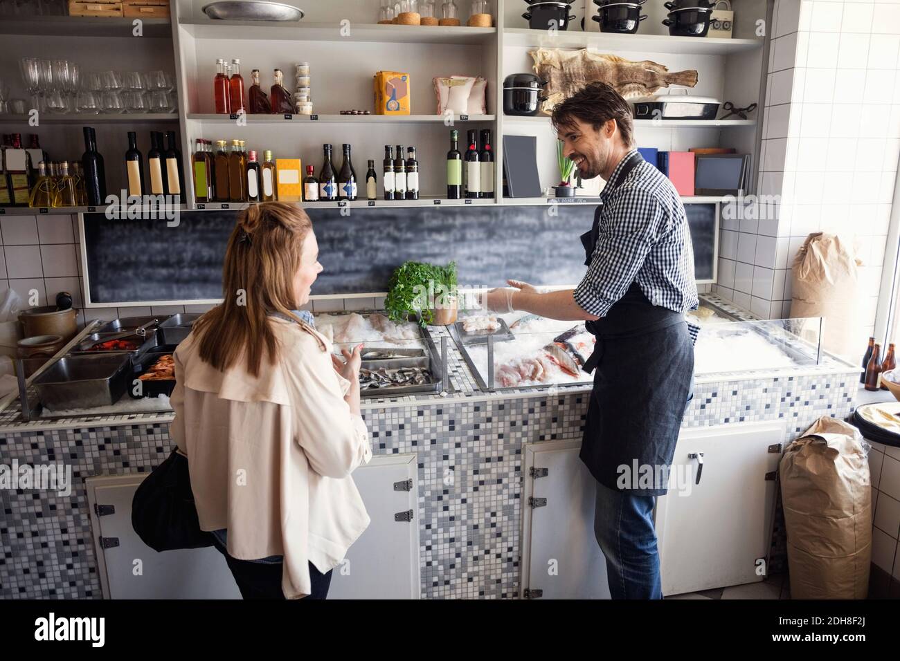 Smiling owner talking to female customer while standing at store Stock ...