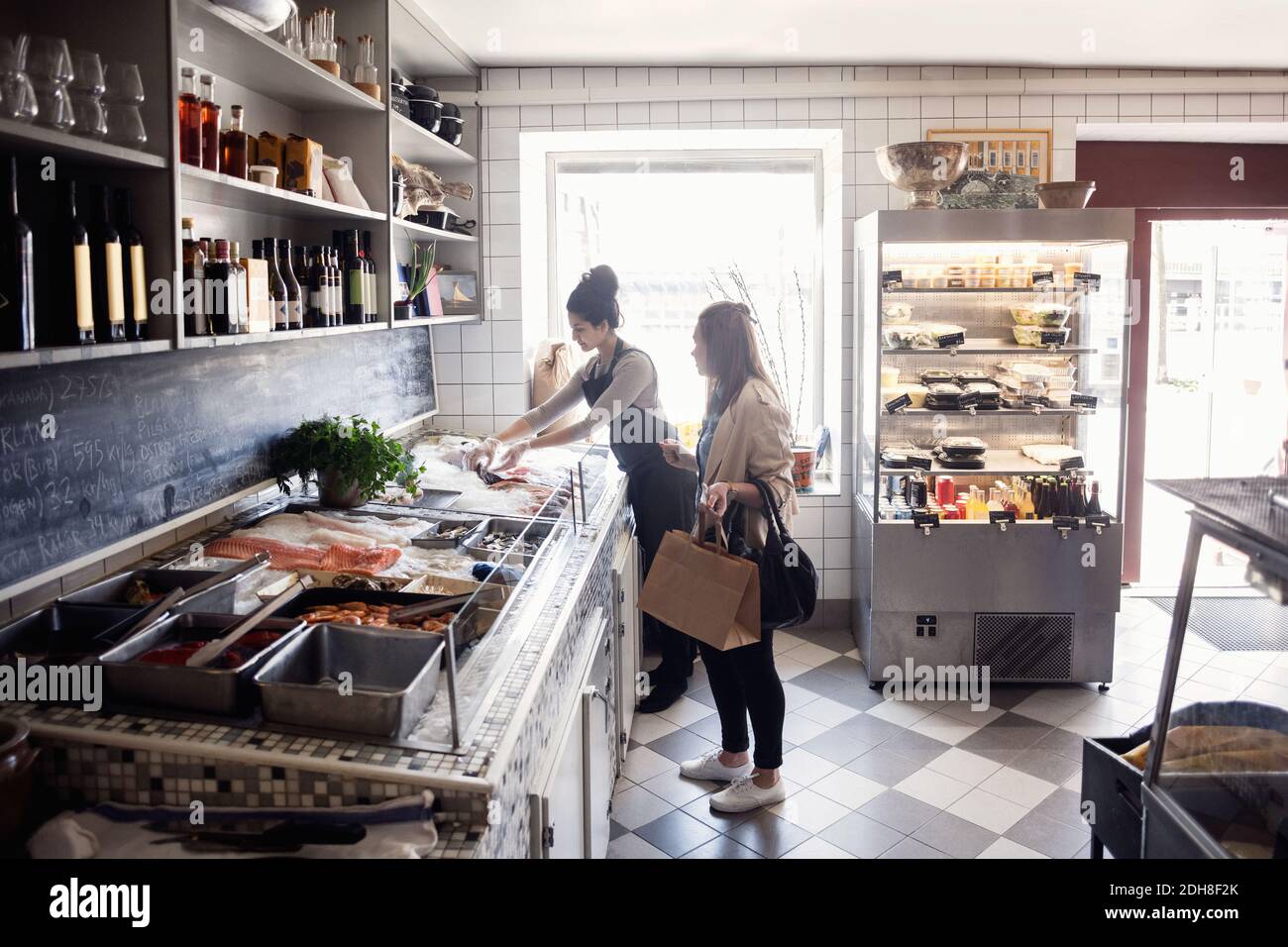 Owner assisting customer while shopping at store Stock Photo - Alamy