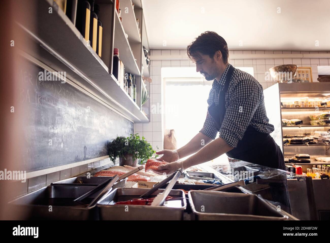 Male worker keeping fresh fish for retail display at fish store Stock ...