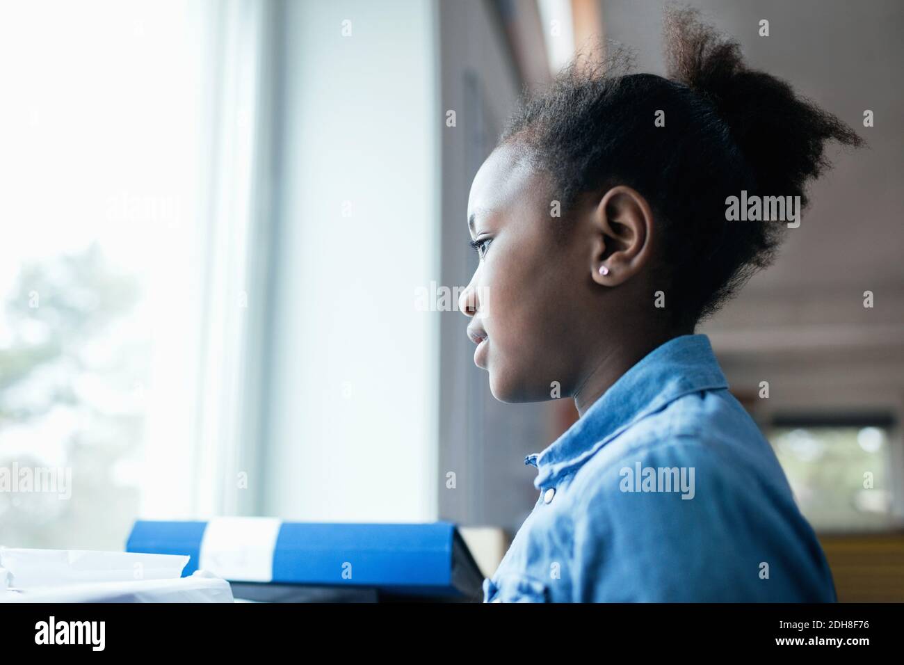 Close-up of thoughtful girl looking through window in classroom Stock ...