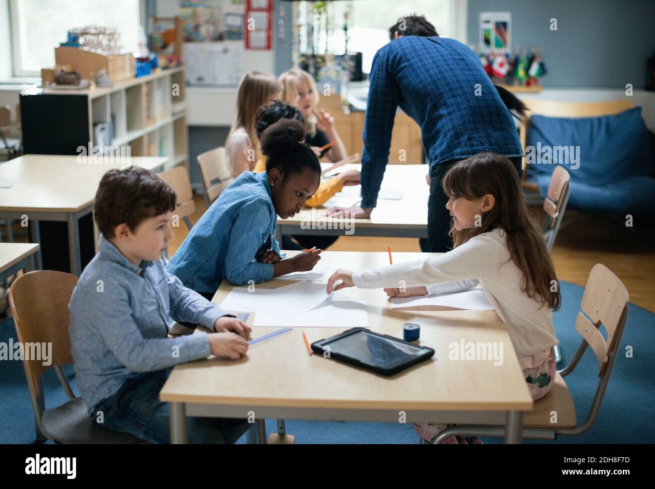 Teacher explaining children sitting in classroom at school Stock Photo ...