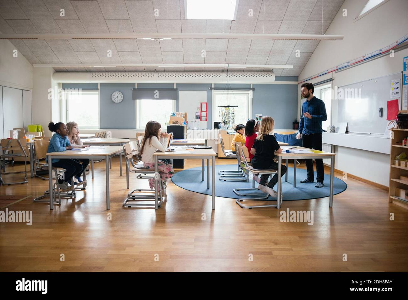 Teacher teaching students in brightly lit classroom at school Stock ...