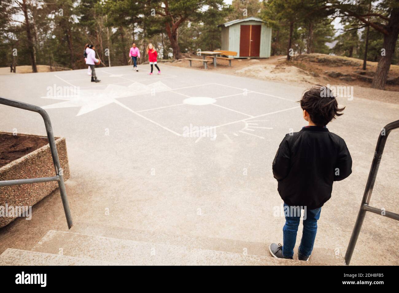 Rear view of boy looking at girls playing on ground at school Stock ...
