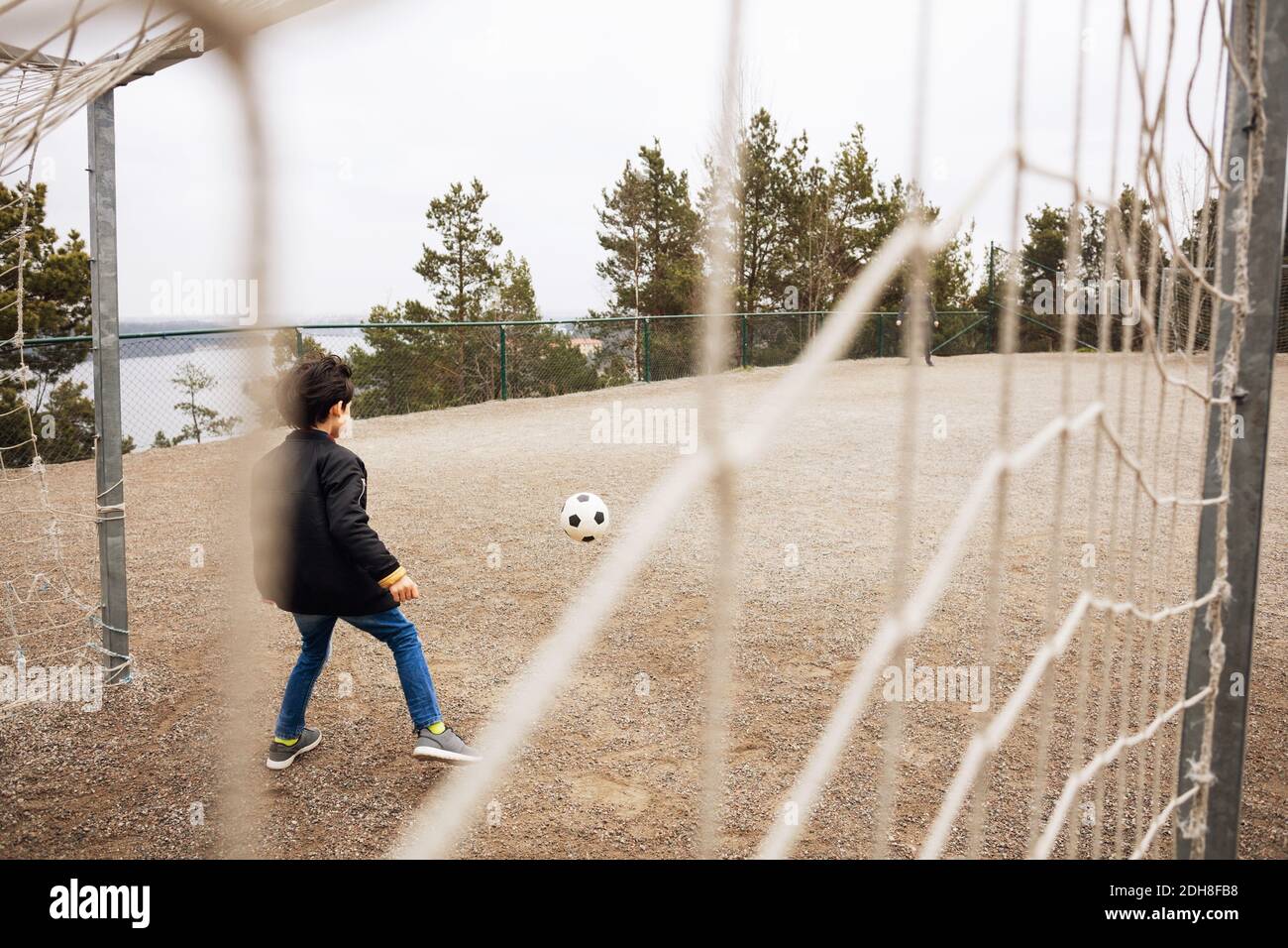Rear view of boy standing on goal post at school playground Stock Photo ...