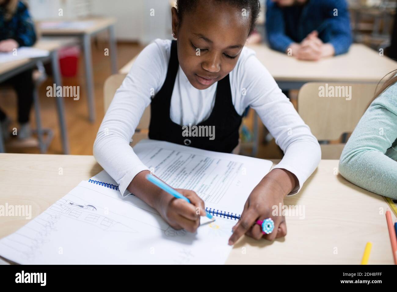 Smiling girl studying at desk in classroom Stock Photo - Alamy