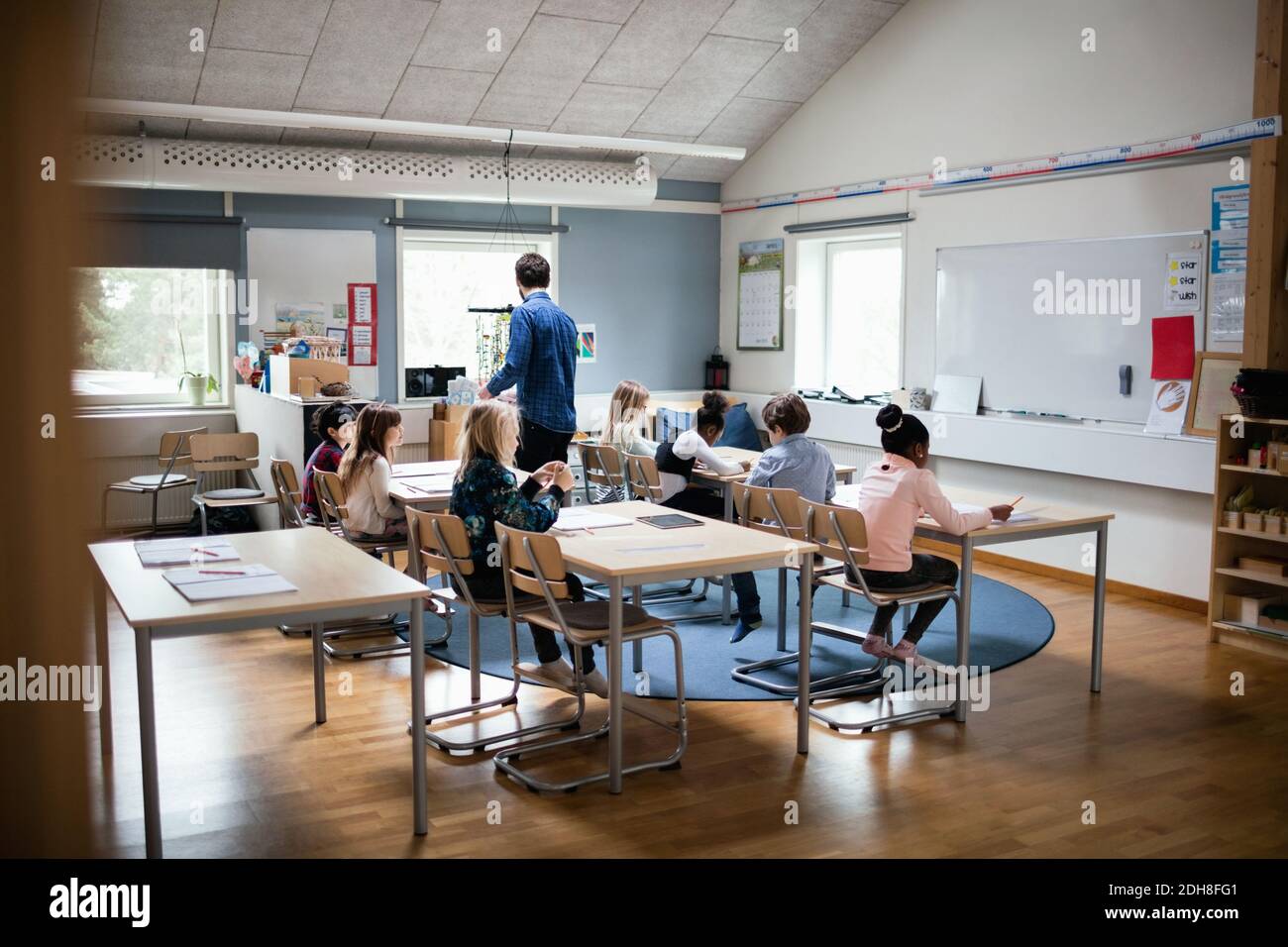 Male teacher teaching students in classroom at school Stock Photo - Alamy