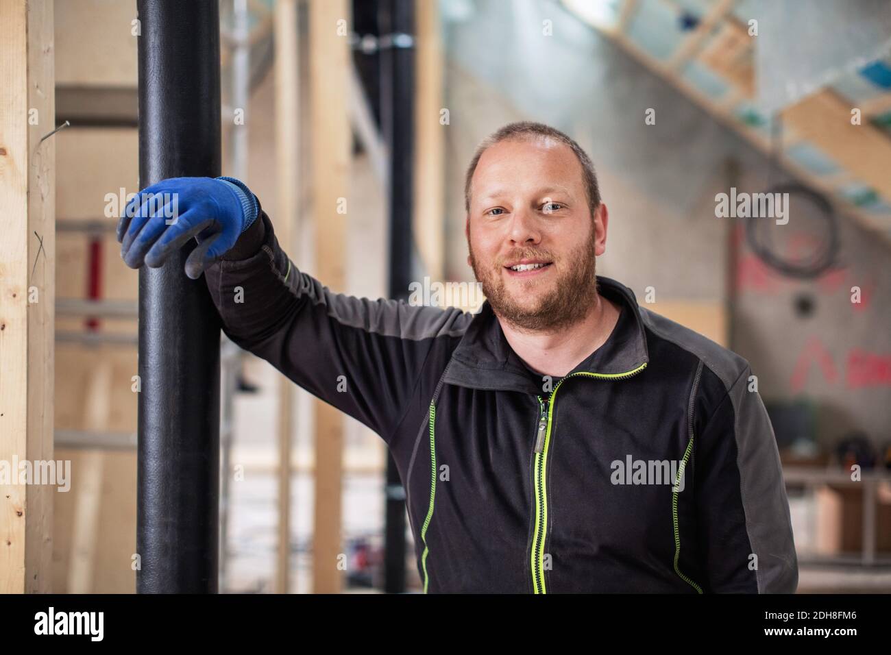 Portrait of engineer leaning by pipe at construction site Stock Photo ...