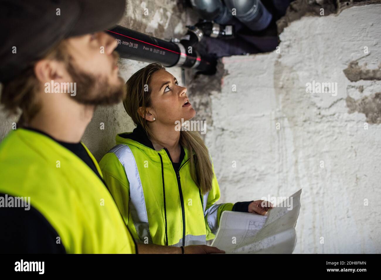 Concentrated male and female plumbers looking up while reading document ...