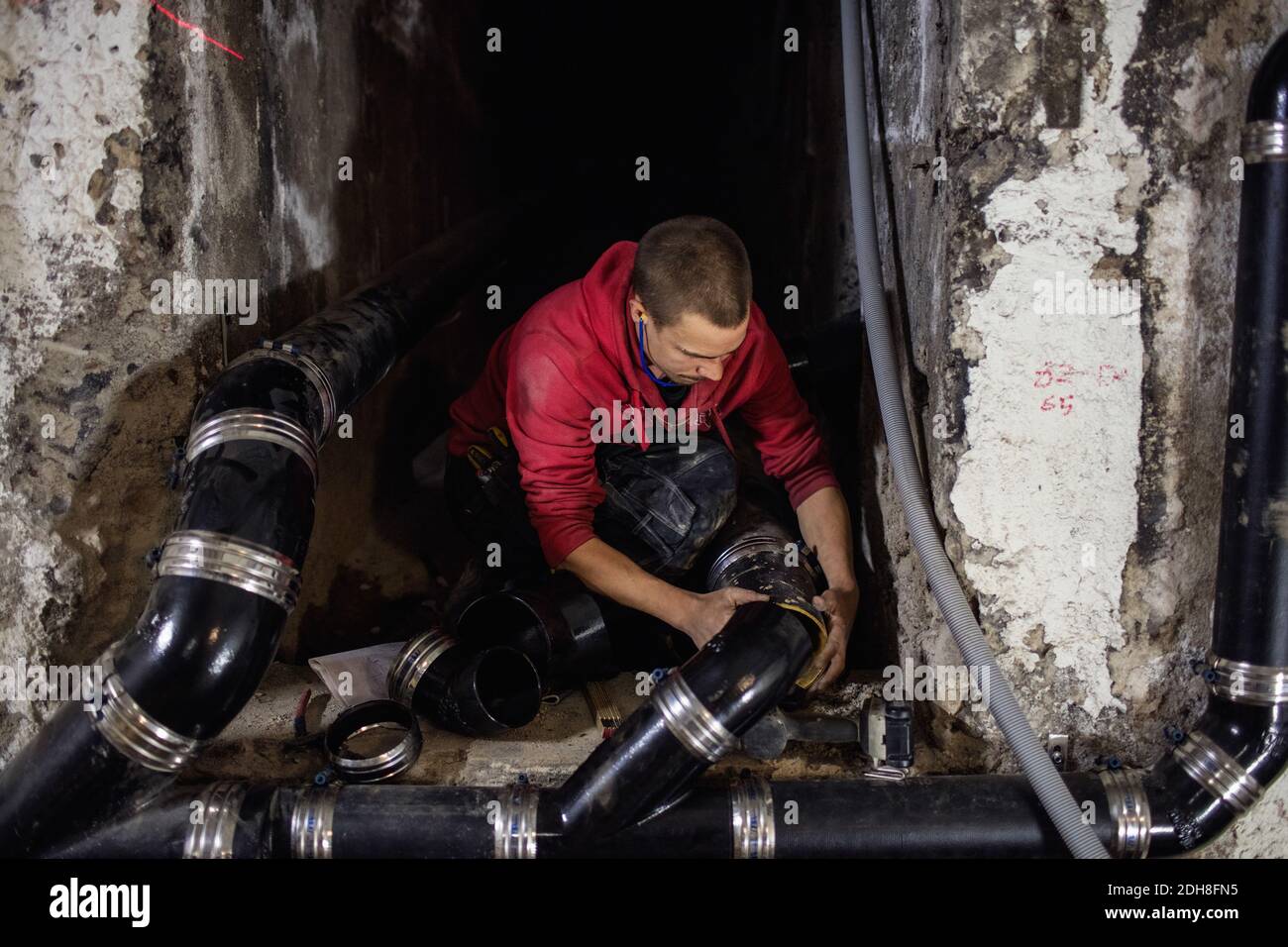 Concentrated plumber connecting pipes in basement Stock Photo - Alamy