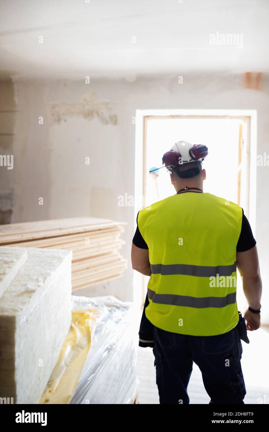 Rear view of man standing in brightly lit room at construction site ...