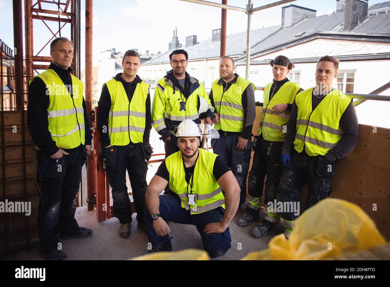 Portrait of confident professional workers posing at construction site ...