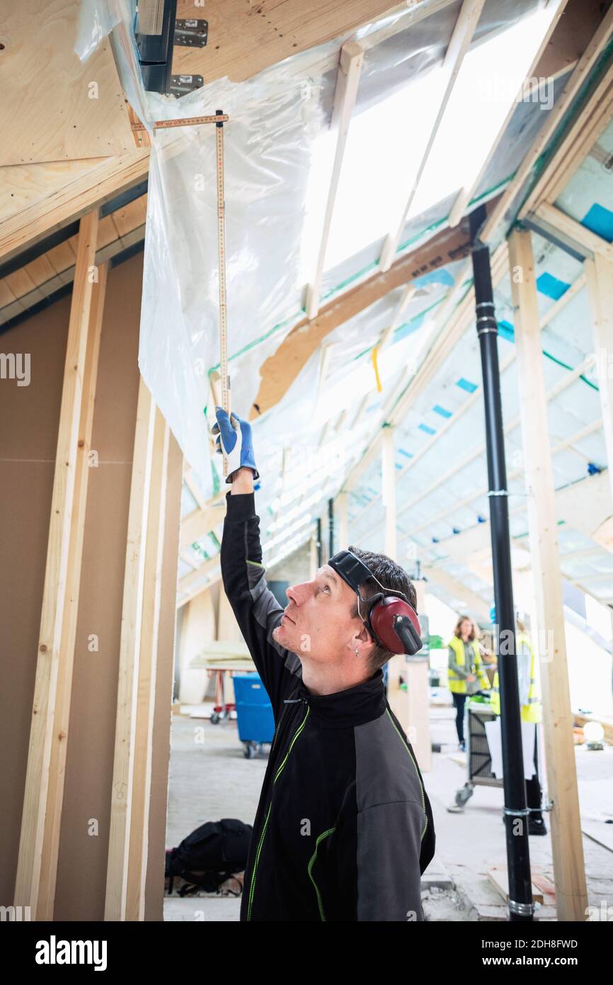 Side view of carpenter measuring height while working at site Stock ...