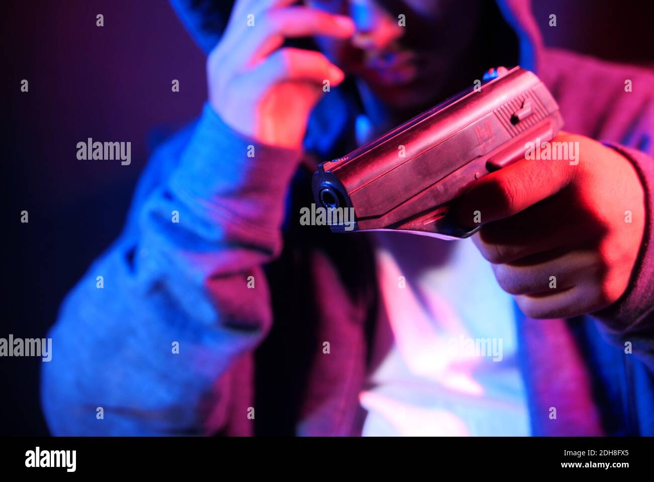 hooded man hand holding gun isolated on black Stock Photo - Alamy