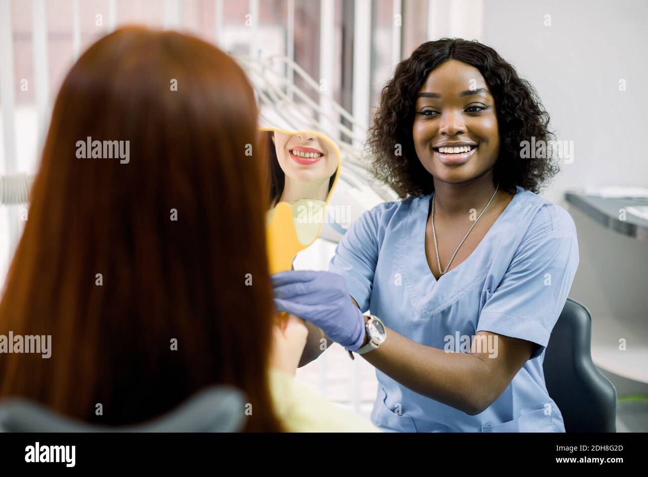Back view of woman patient looking at her smile after curing or ...