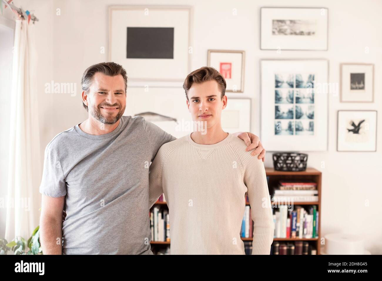 Portrait of confident father and son standing with arms around at new ...
