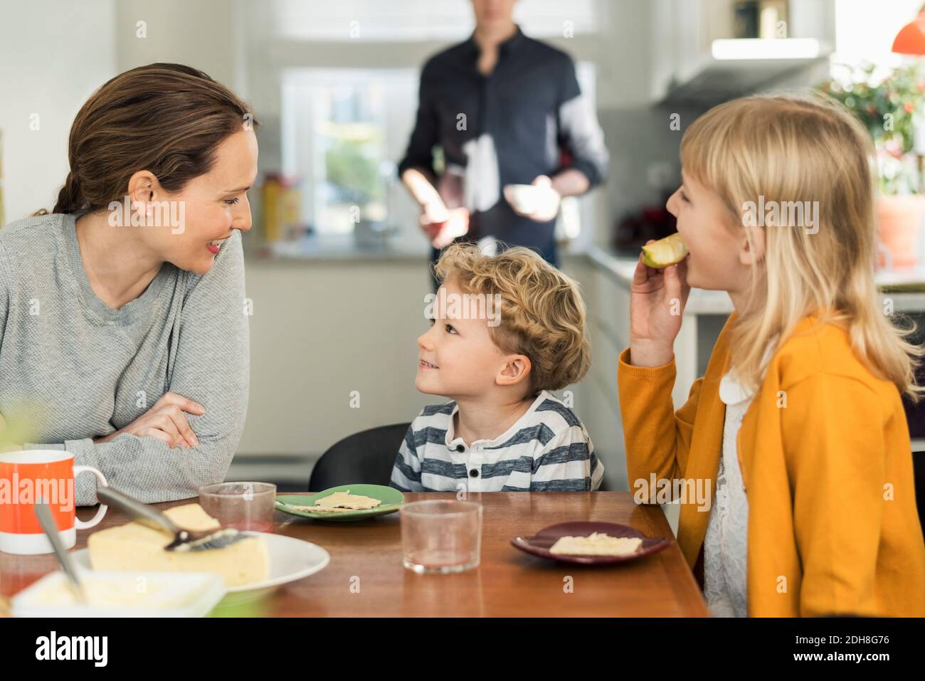 Family eating breakfast at dining table in living room Stock Photo - Alamy