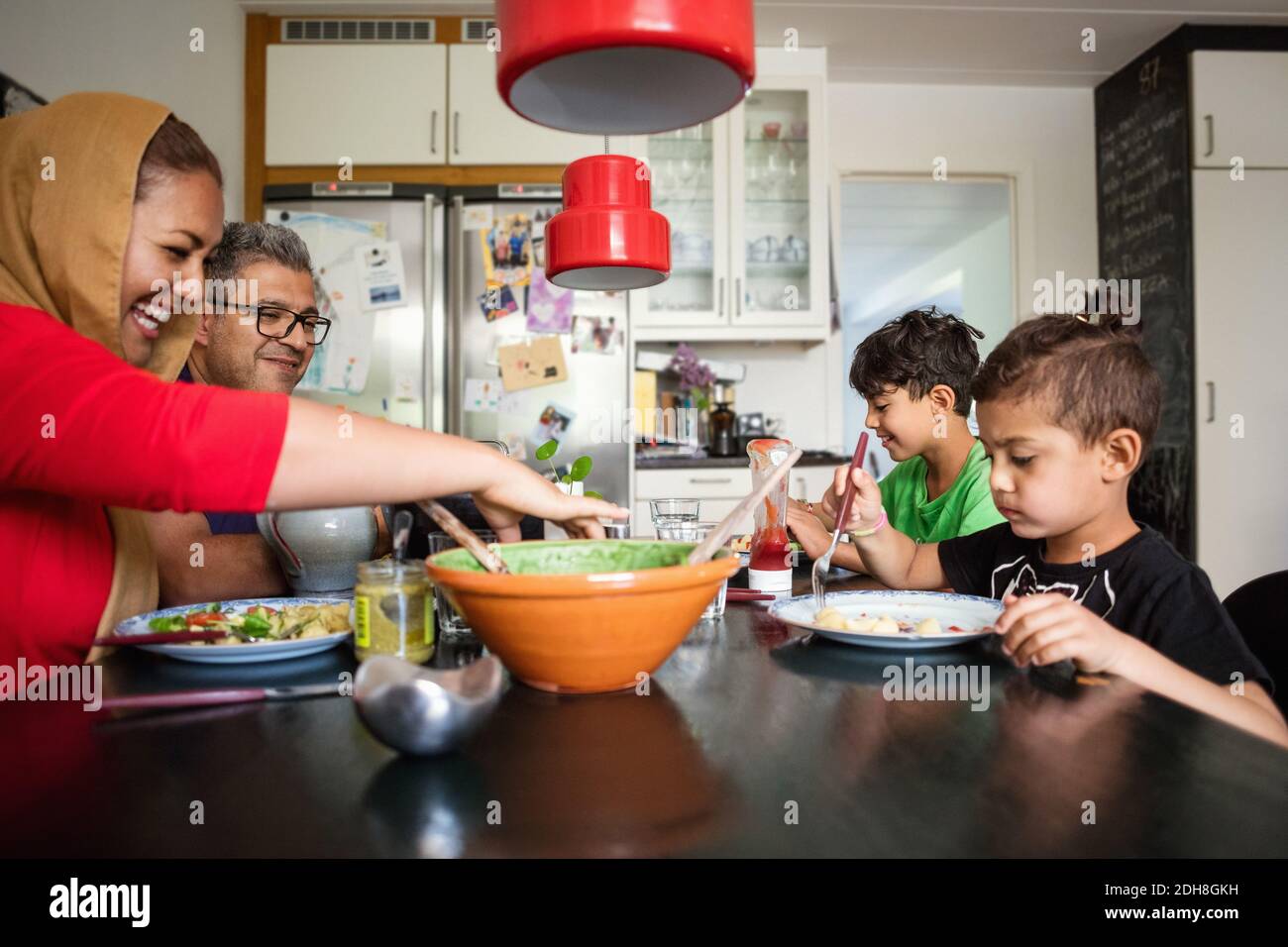 Happy family having meal at dining table Stock Photo - Alamy