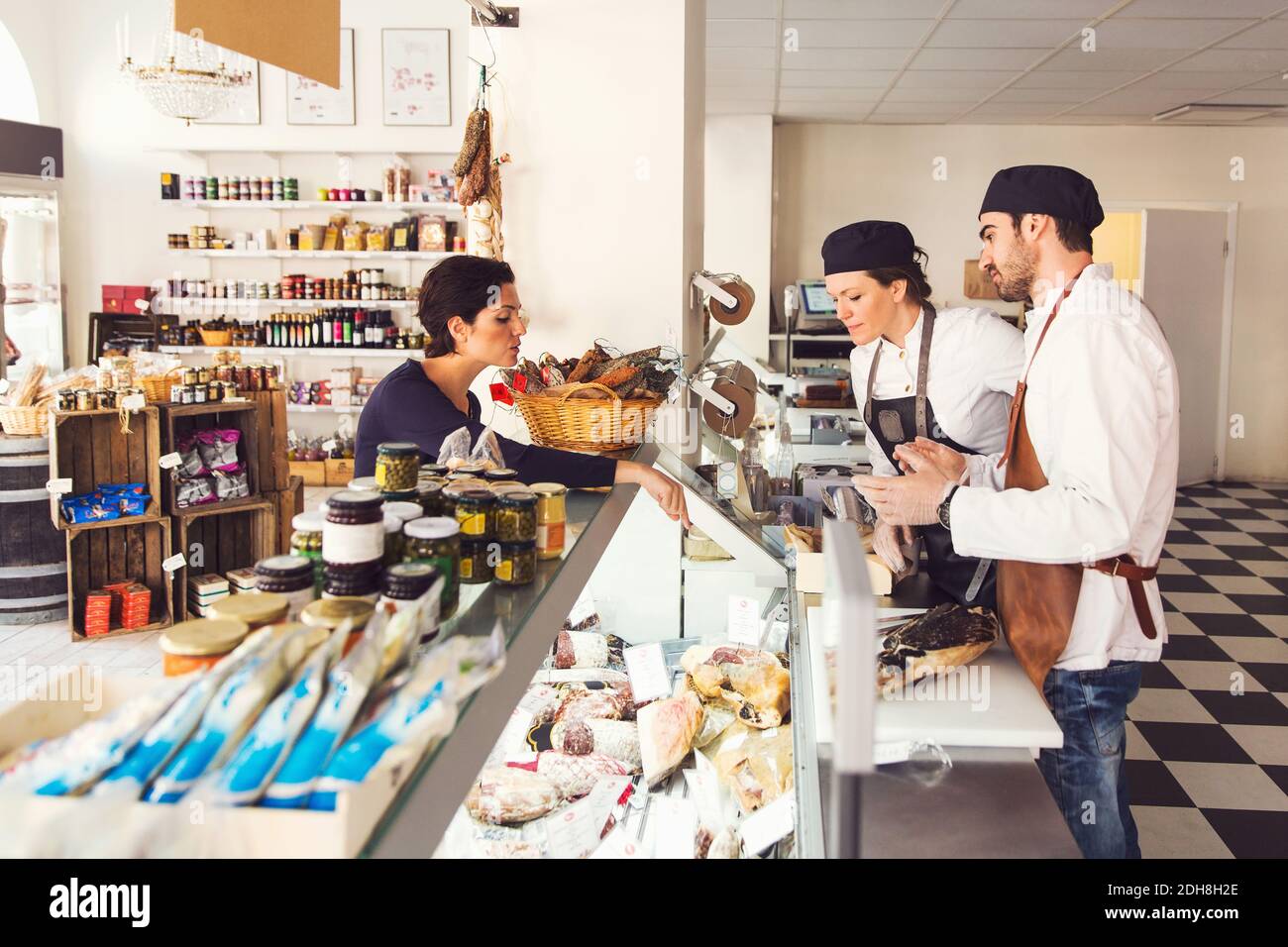 Side view of woman buying grocery from owners at store Stock Photo - Alamy