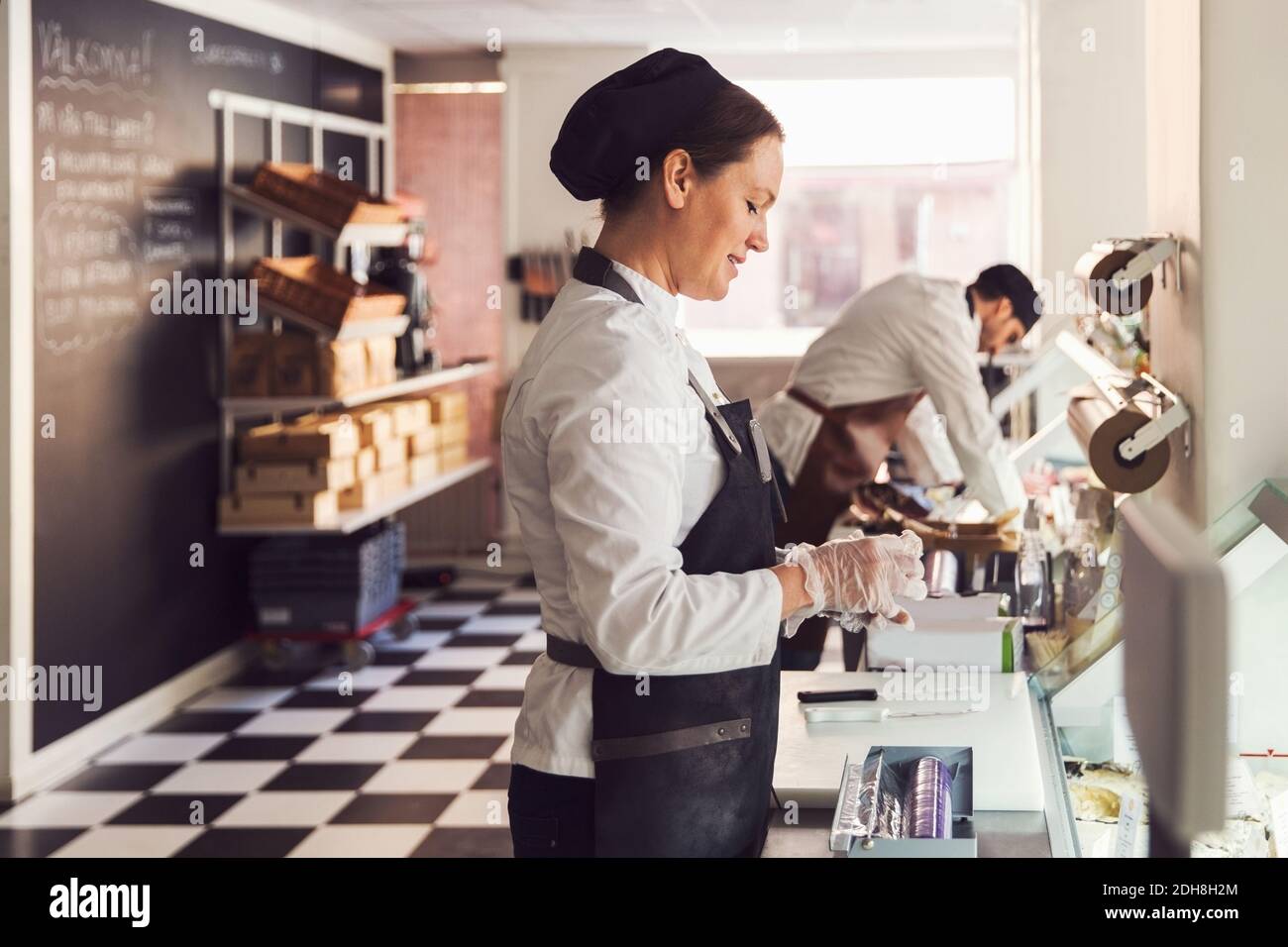 Side view of owners working at counter in grocery store Stock Photo - Alamy