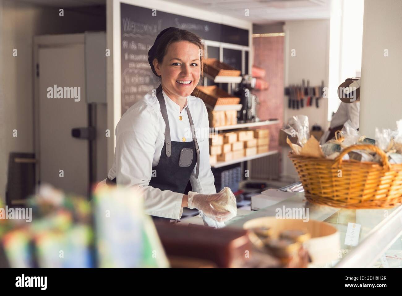 Portrait of happy female owner working at display cabinet in grocery ...