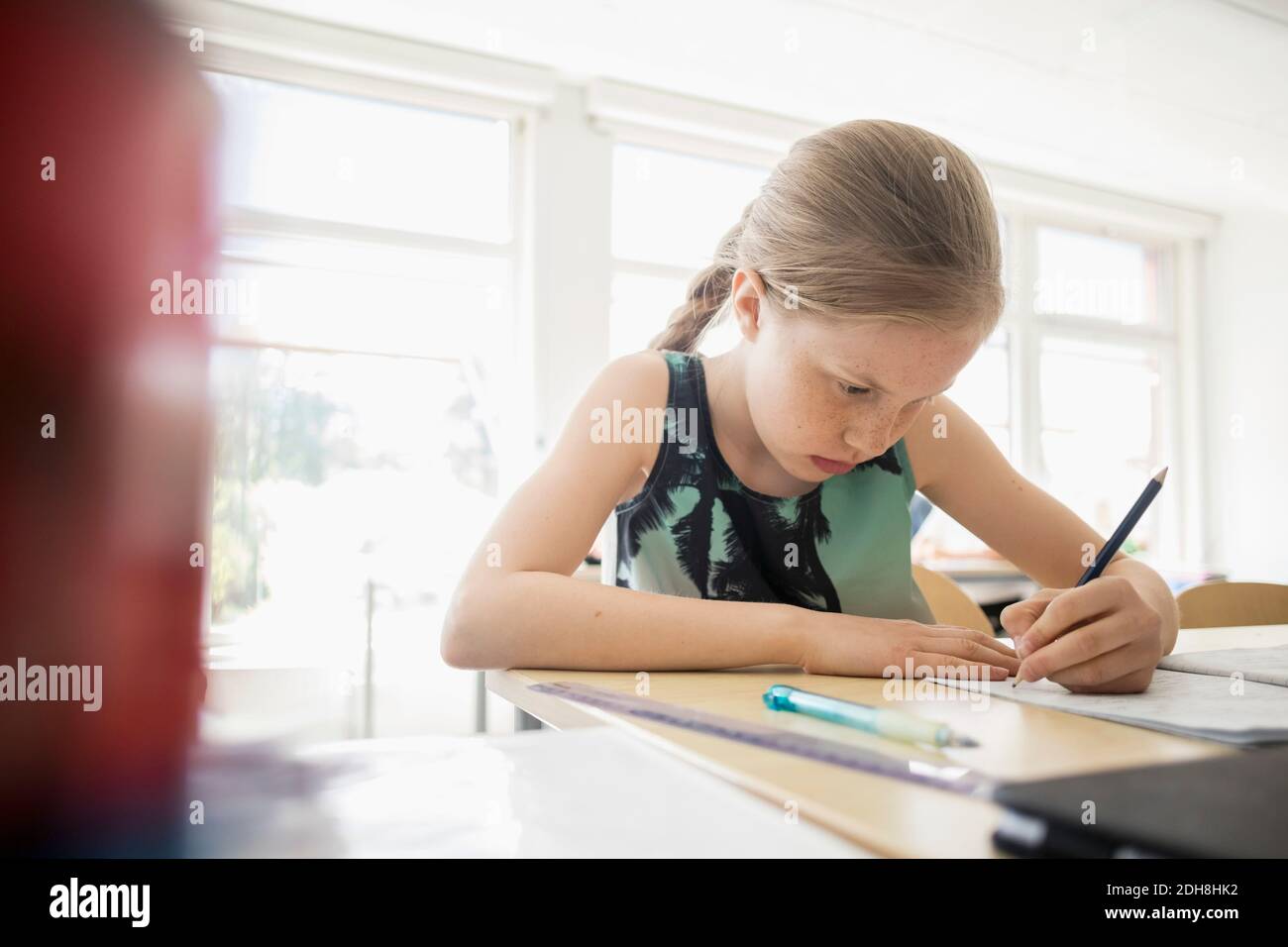 Girl writing in book against window at classroom Stock Photo - Alamy