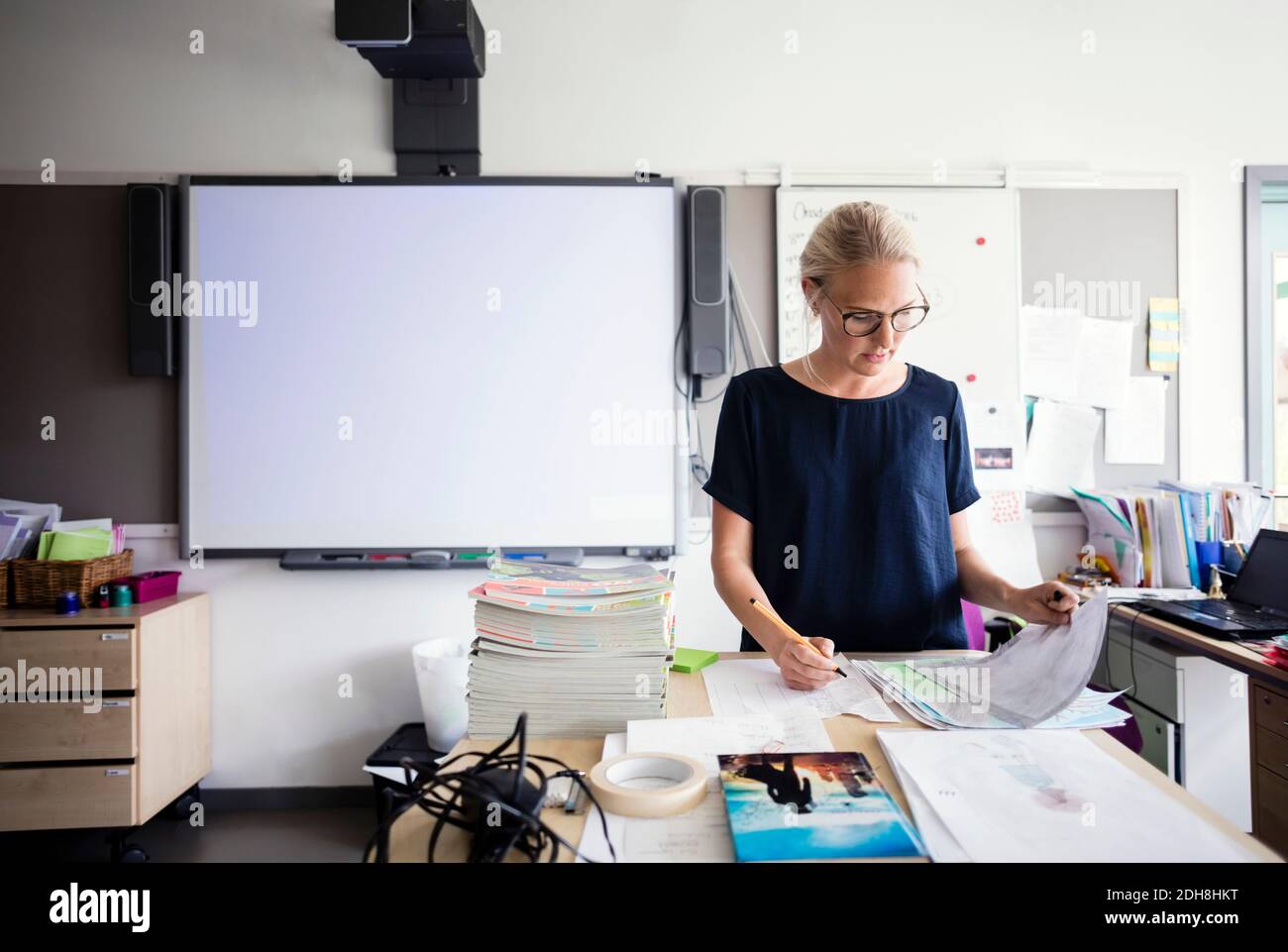 Teacher writing on paper against blank whiteboard in classroom Stock ...