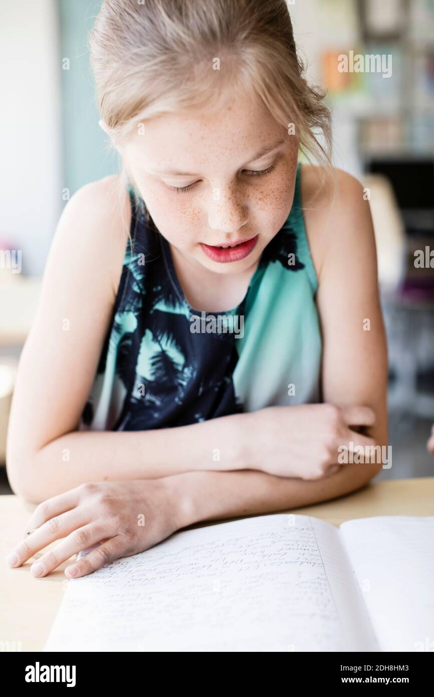 Girl reading book in classroom Stock Photo - Alamy
