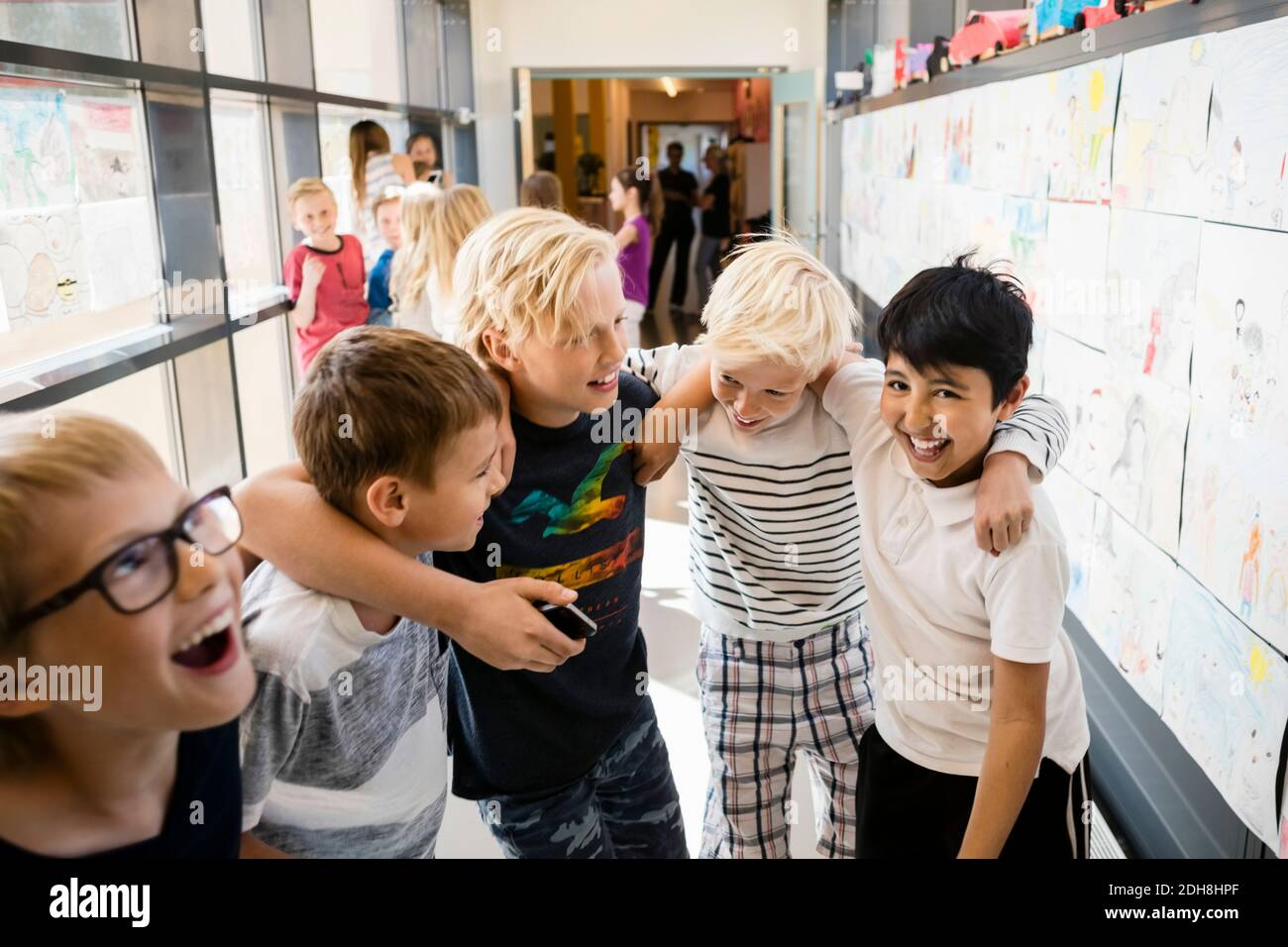Tilt shot of cheerful friends in school corridor Stock Photo - Alamy