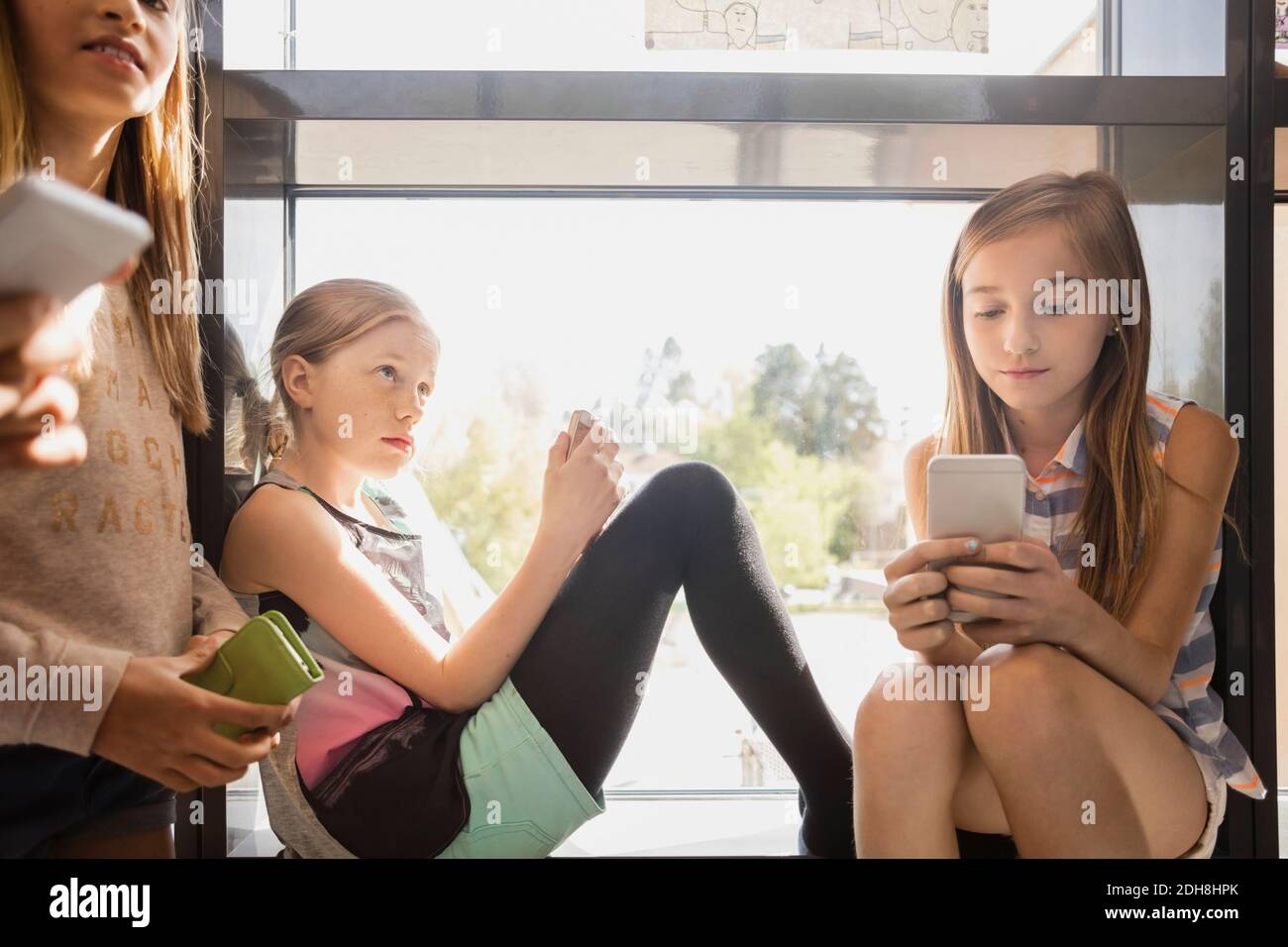 Students using mobile phones in corridor Stock Photo - Alamy