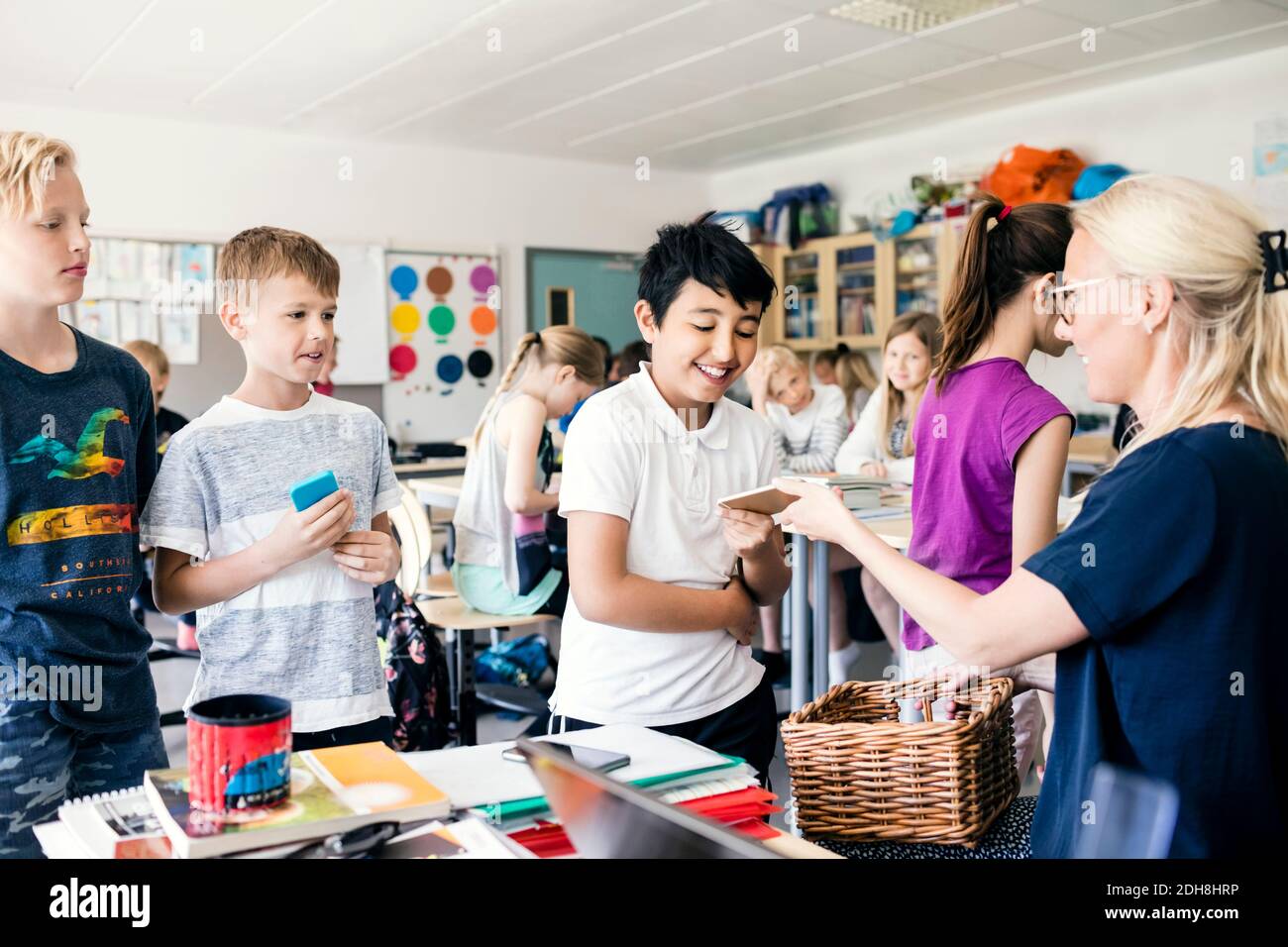 Teacher giving mobile phone to student at classroom Stock Photo - Alamy