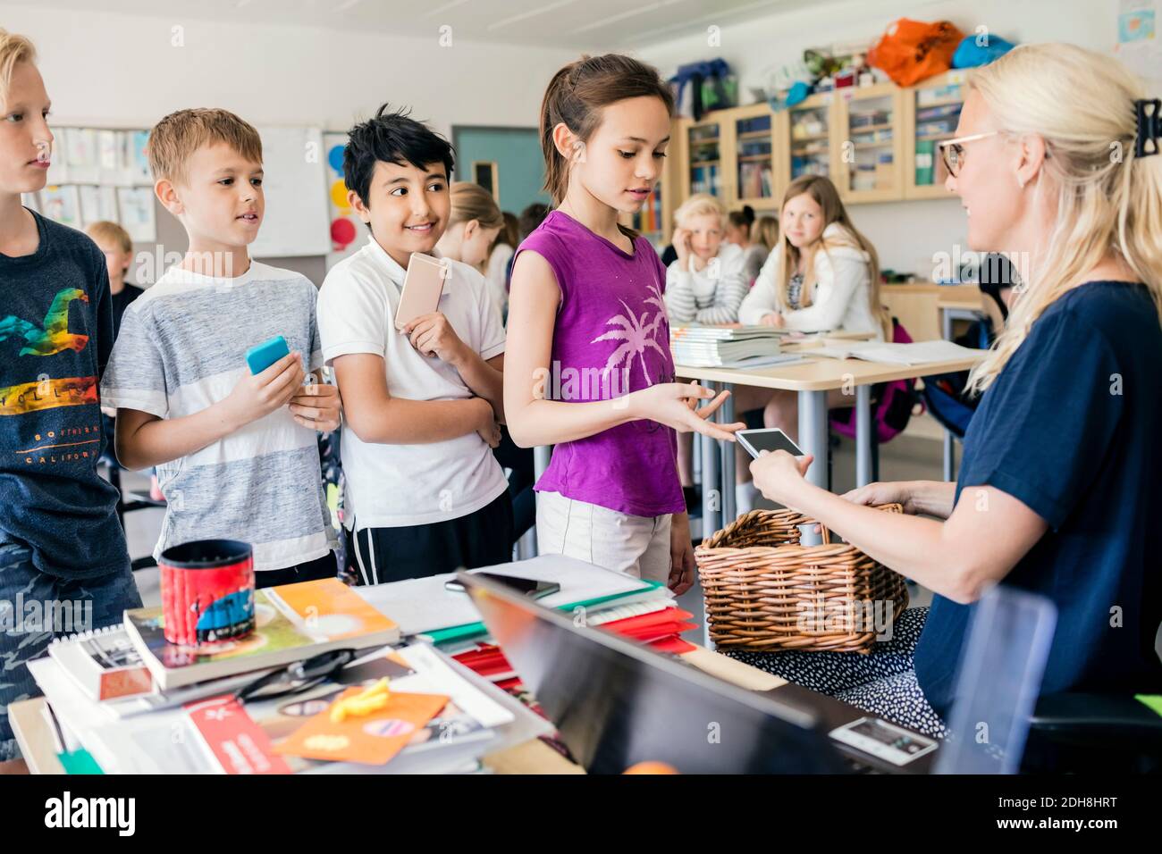 Students showing mobile phone to teacher at classroom Stock Photo - Alamy