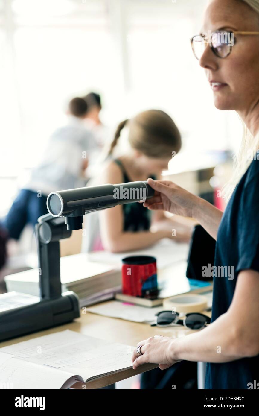 Teacher using camera for reading book at classroom Stock Photo - Alamy