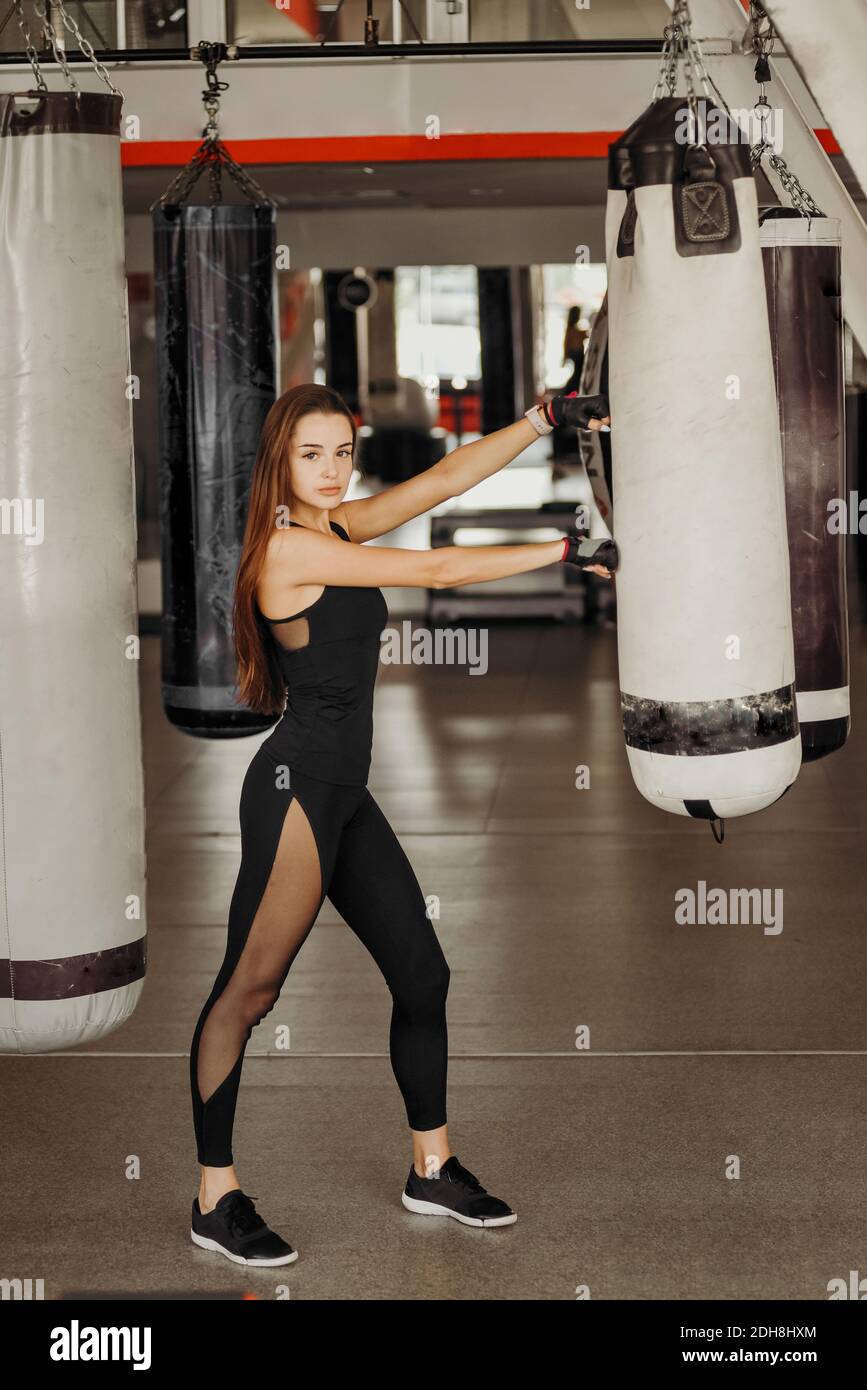 Fit woman and punching bag during training in the gym at the fitness ...