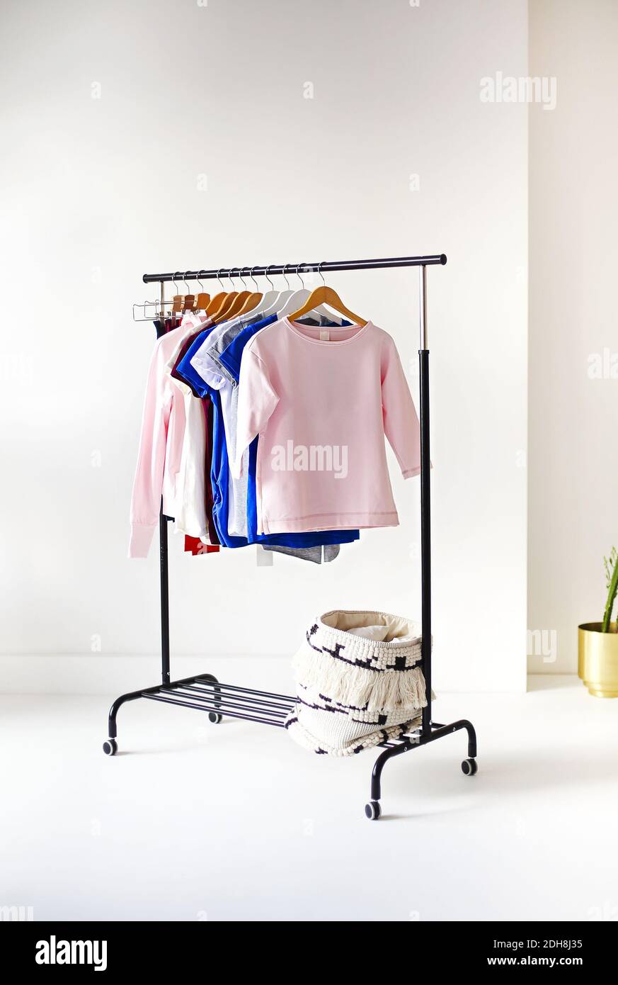 Colorful clothes hanging on rack in room Stock Photo - Alamy