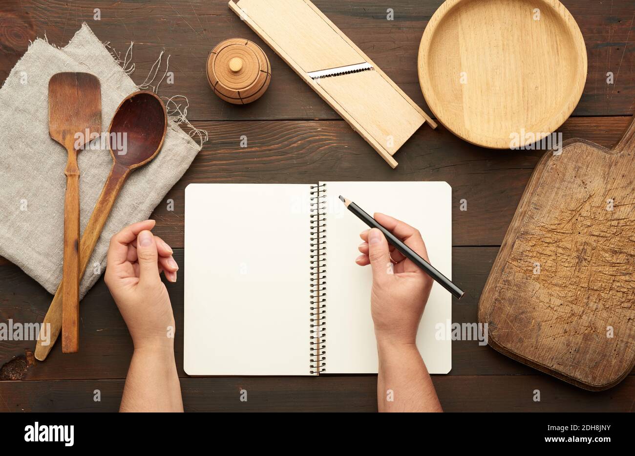 Open notebook with blank white sheets and kitchen utensils on a brown ...